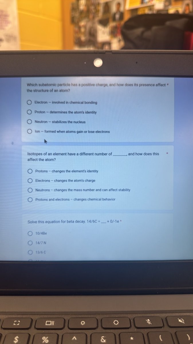 Which subatomic particle has a positive charge, and how does its presence..